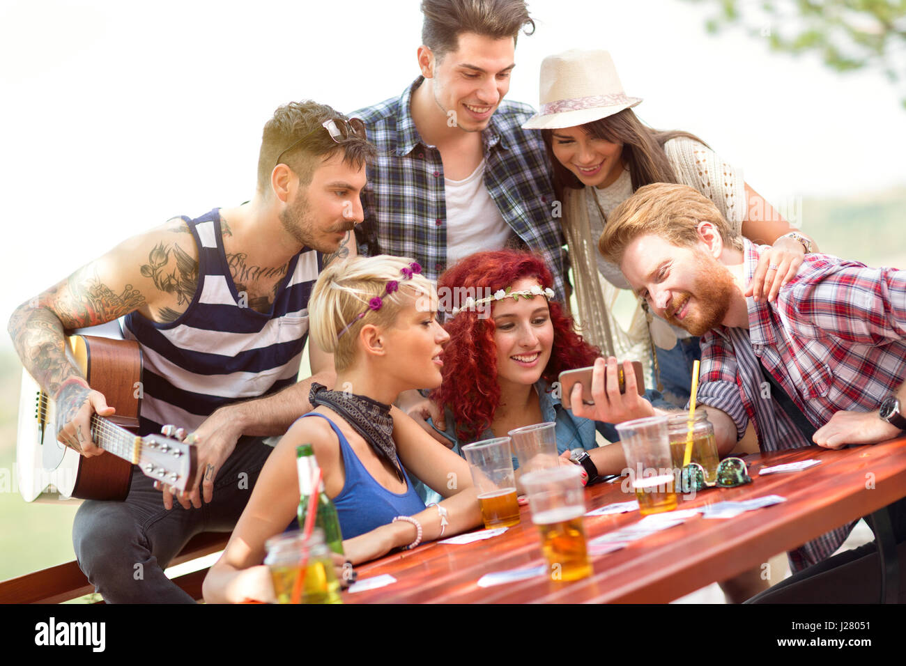 Young group of friends look at screen of guys mobile phone outside ...