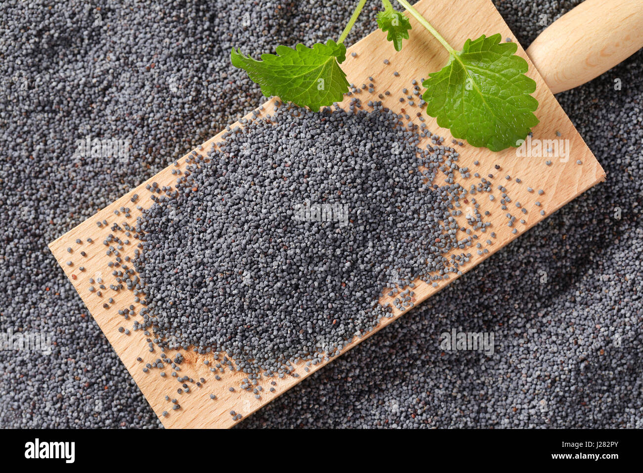 Whole black poppy seeds on cutting board and around it Stock Photo - Alamy