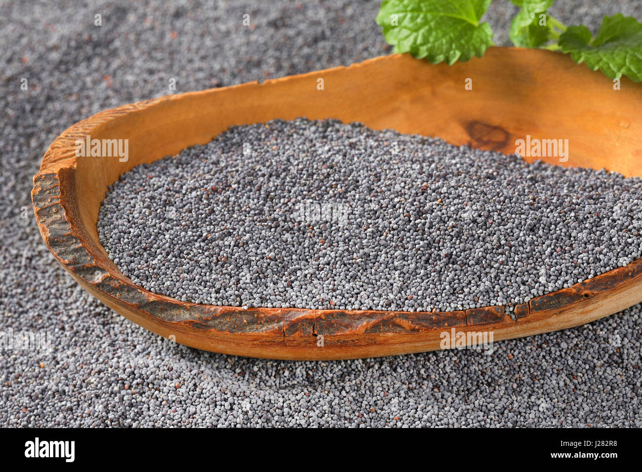 black poppy seeds in olive wood bowl and around it Stock Photo - Alamy