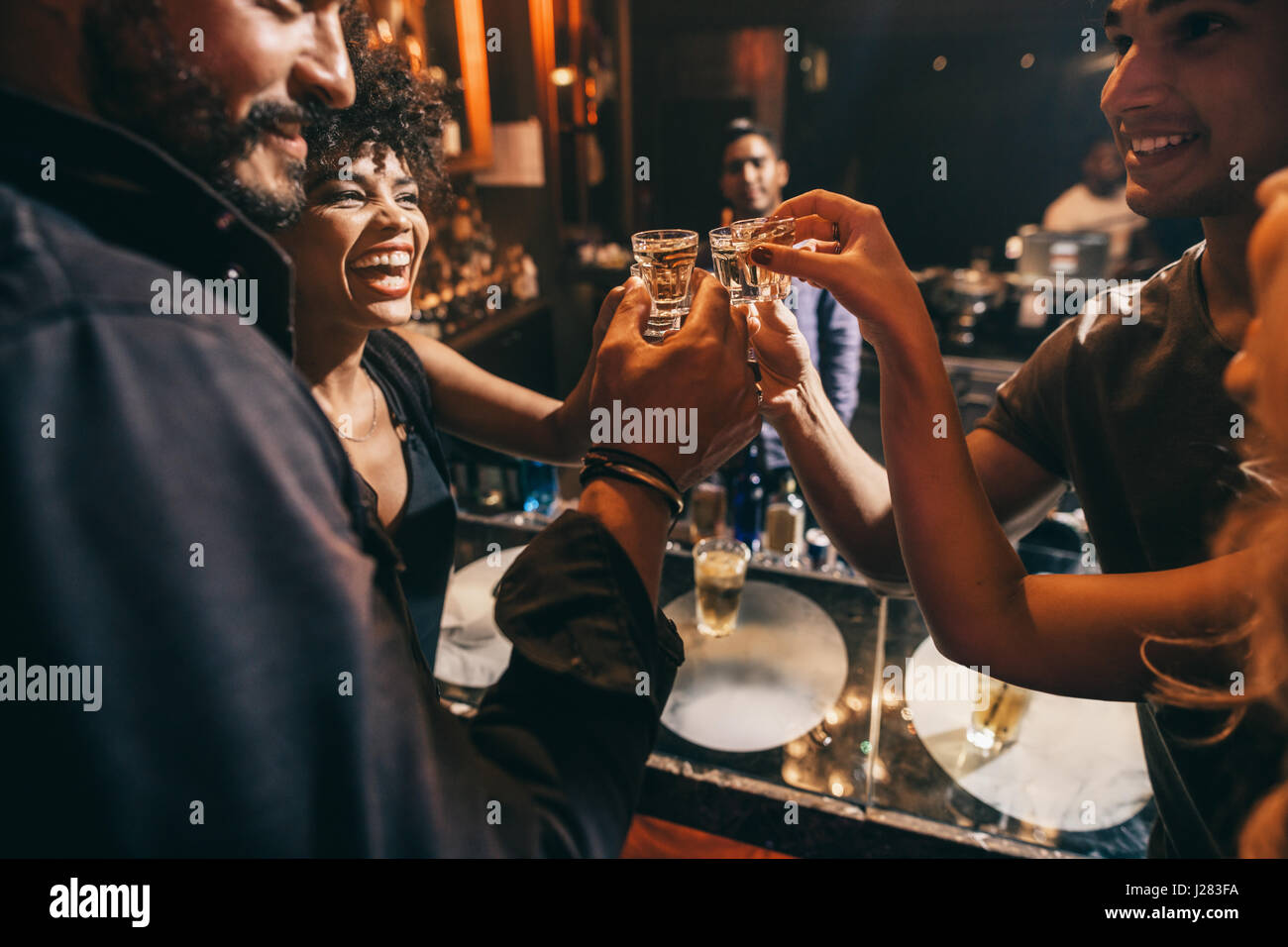 Friends toasting each other with shots of vodka as they enjoy a ...