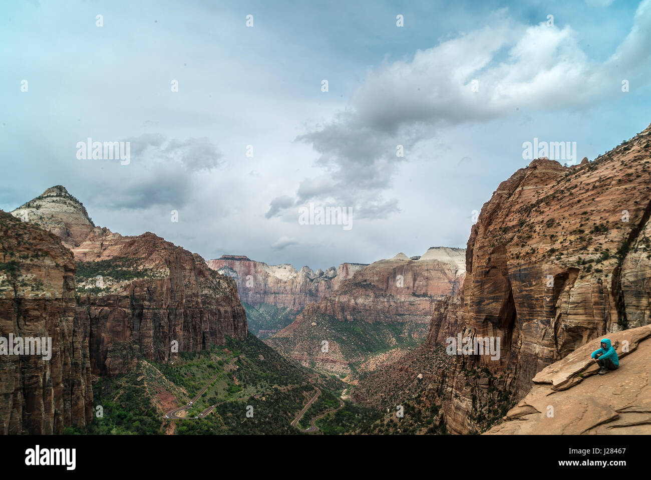 Female hiker sitting on rocky mountains against cloudy sky at Zion ...