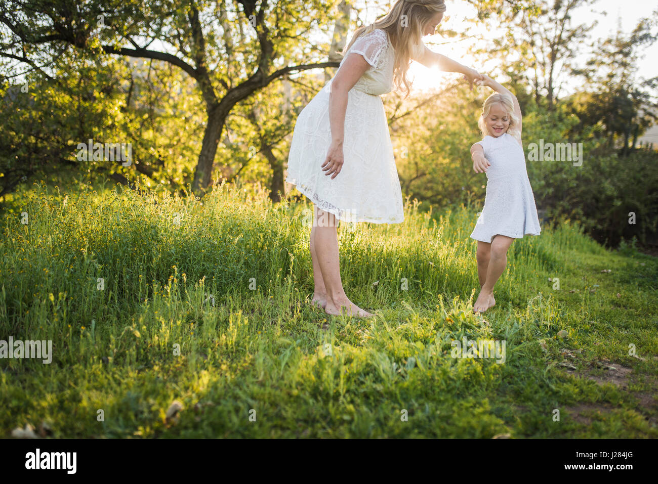 Pregnant mother dancing with daughter on grassy field in park Stock ...