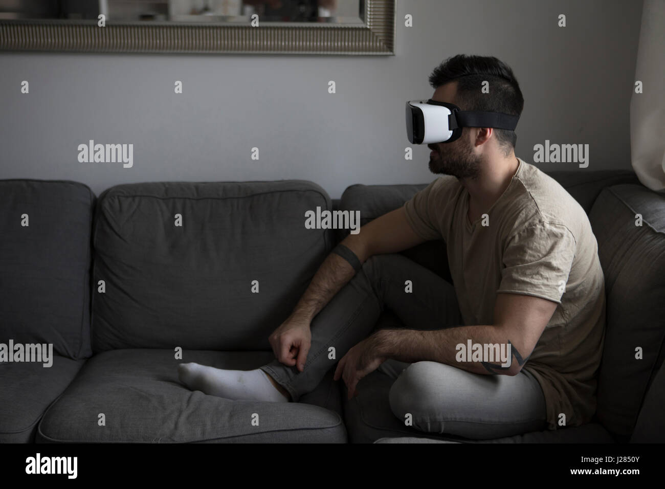 Man using virtual reality simulator while sitting sofa at home Stock ...