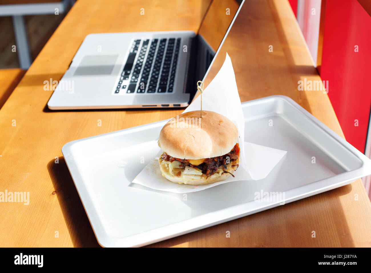 Eating at work place - fast food. burger near laptop. lunch break while ...