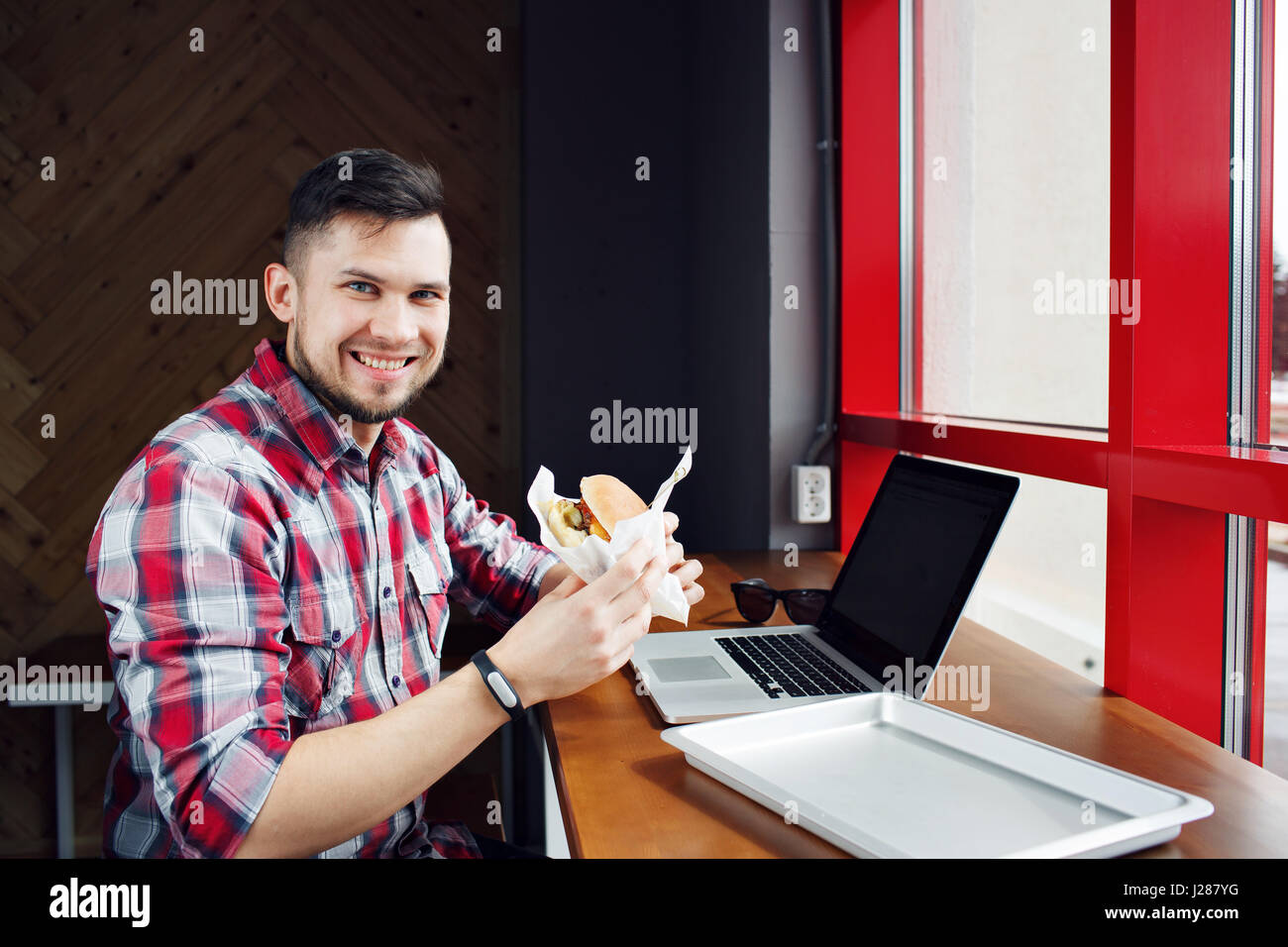 Eating at work place - fast food. burger near laptop. lunch break while ...
