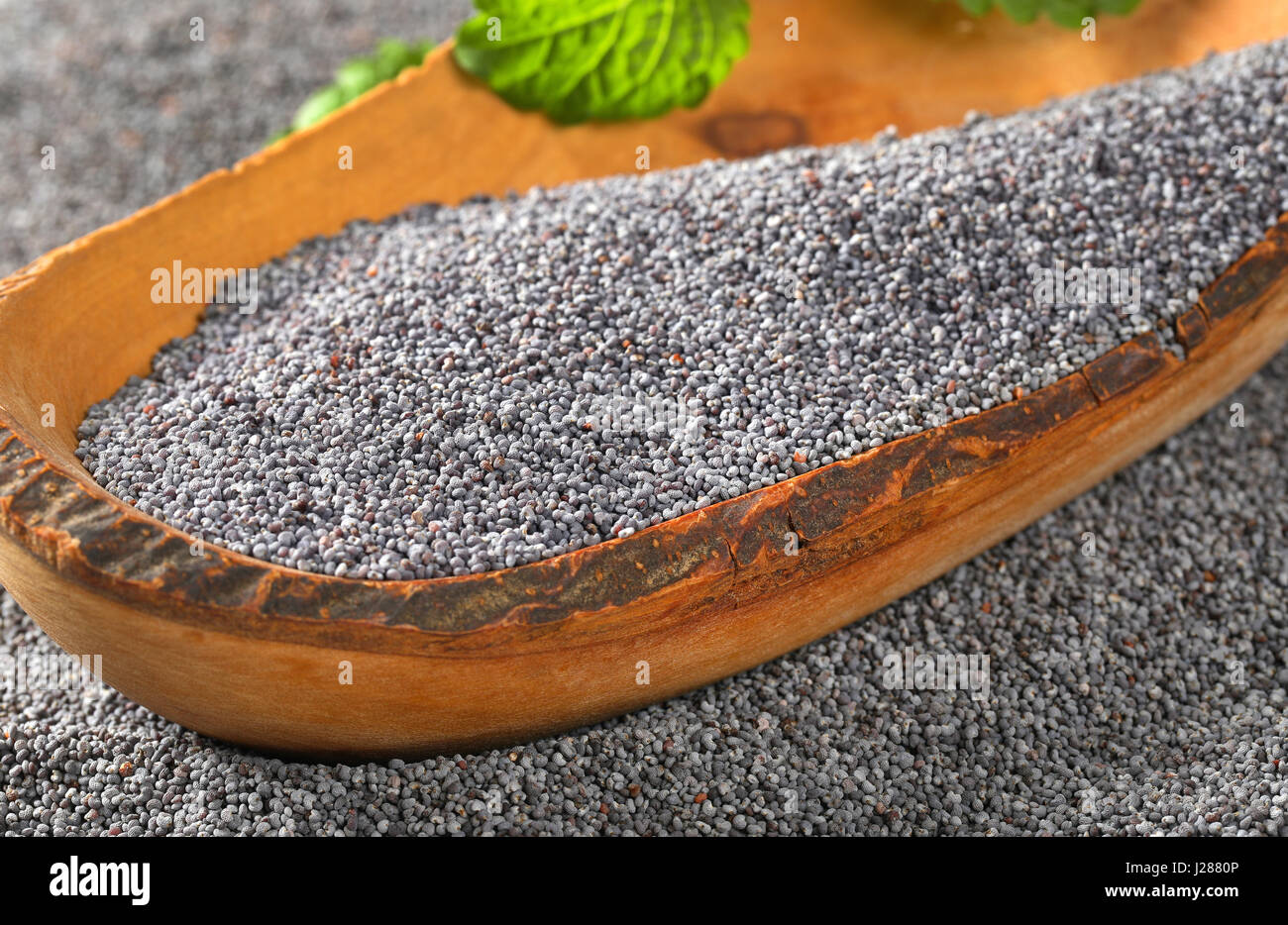 black poppy seeds in olive wood bowl and around it Stock Photo - Alamy