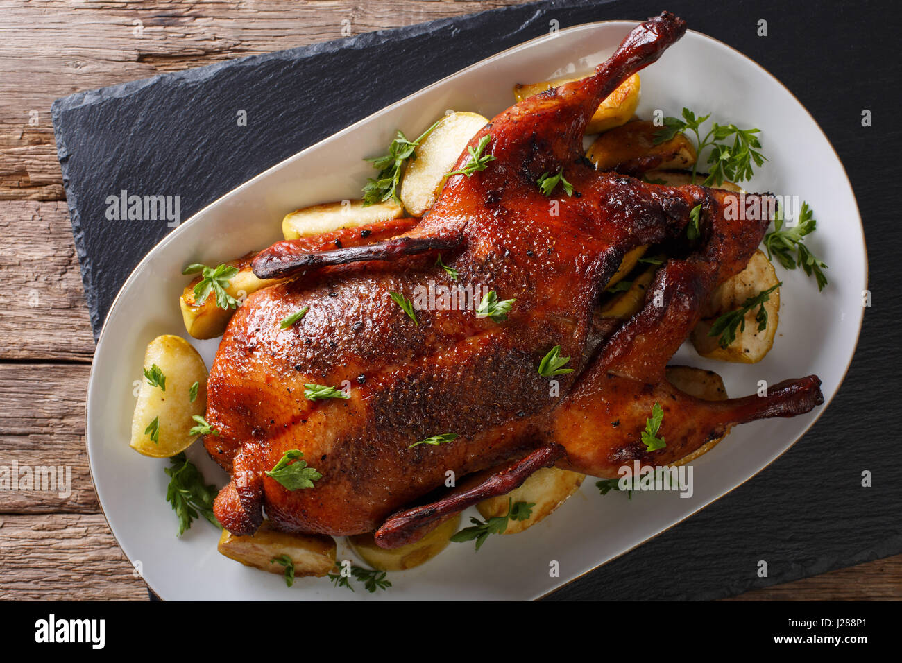 Delicious whole baked duck with apples close-up on a platter on the ...
