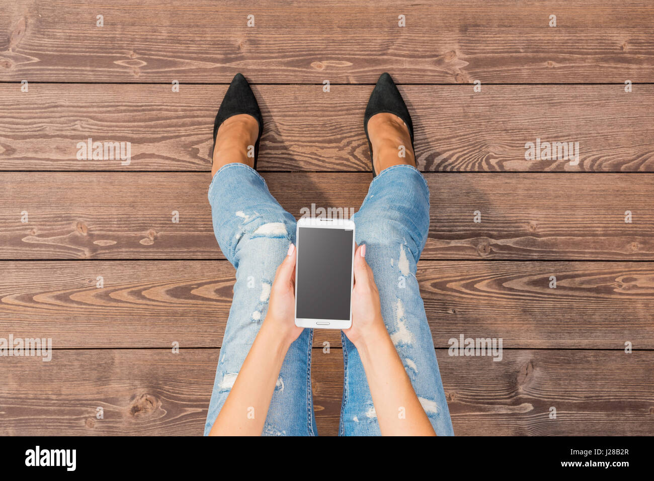 Fashionable woman using smart phone over wooden floor Stock Photo - Alamy
