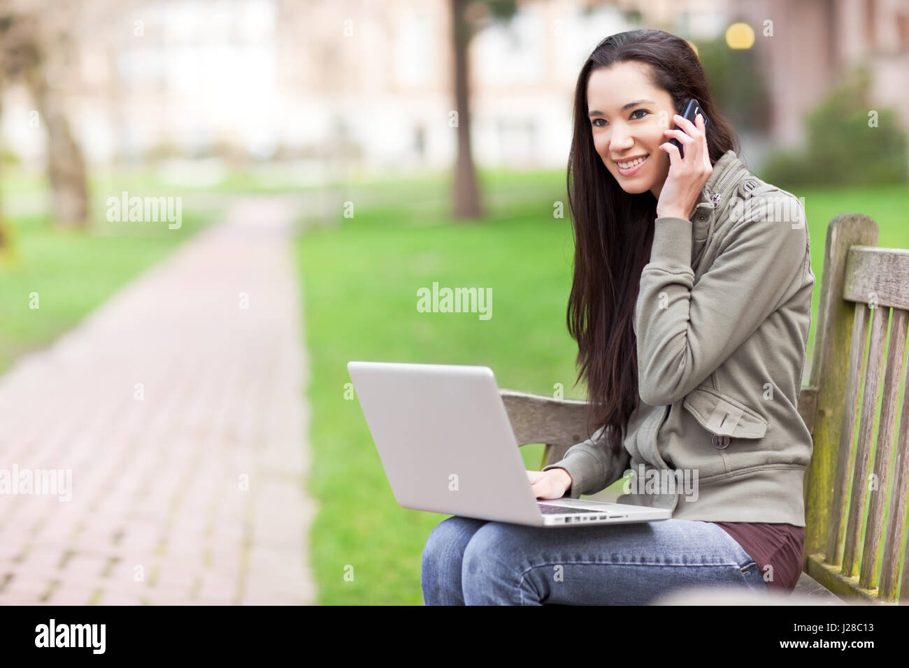 A beautiful ethnic college student talking on the phone working on her ...