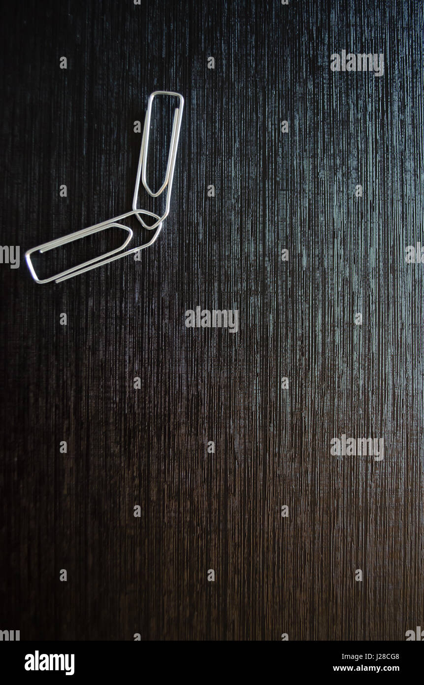 Two connected paper clips on dark background Stock Photo - Alamy
