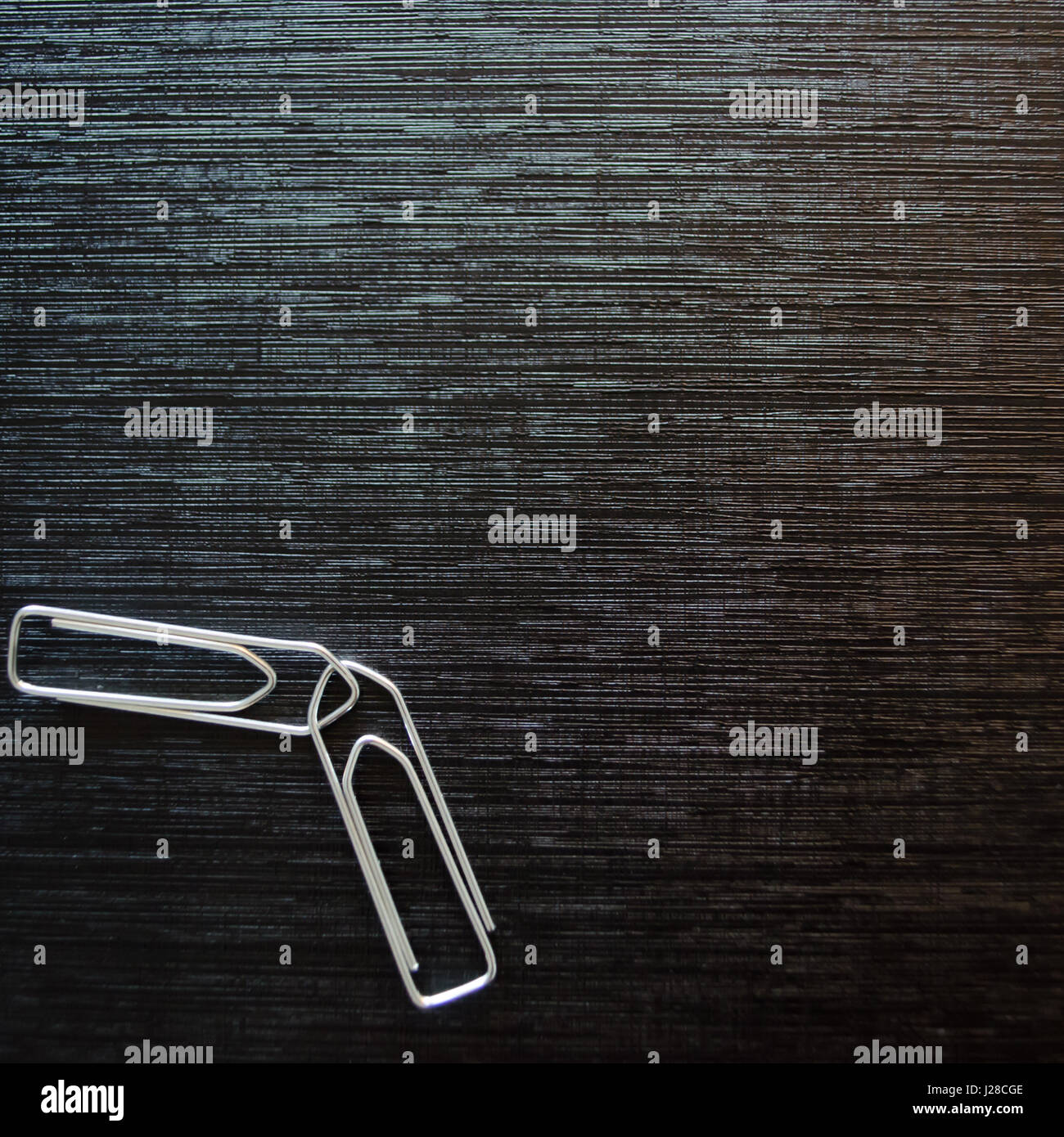 Two connected paper clips on dark background Stock Photo - Alamy