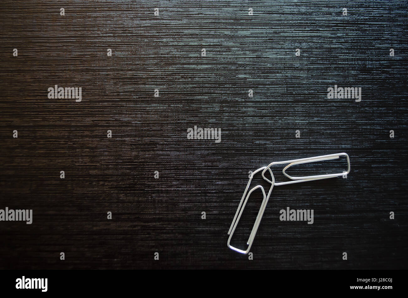 Two connected paper clips on dark background Stock Photo - Alamy