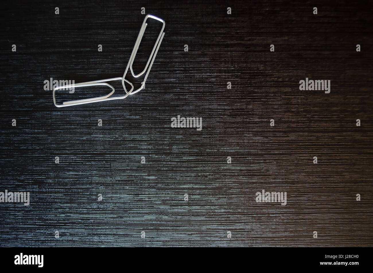 Two connected paper clips on dark background Stock Photo - Alamy