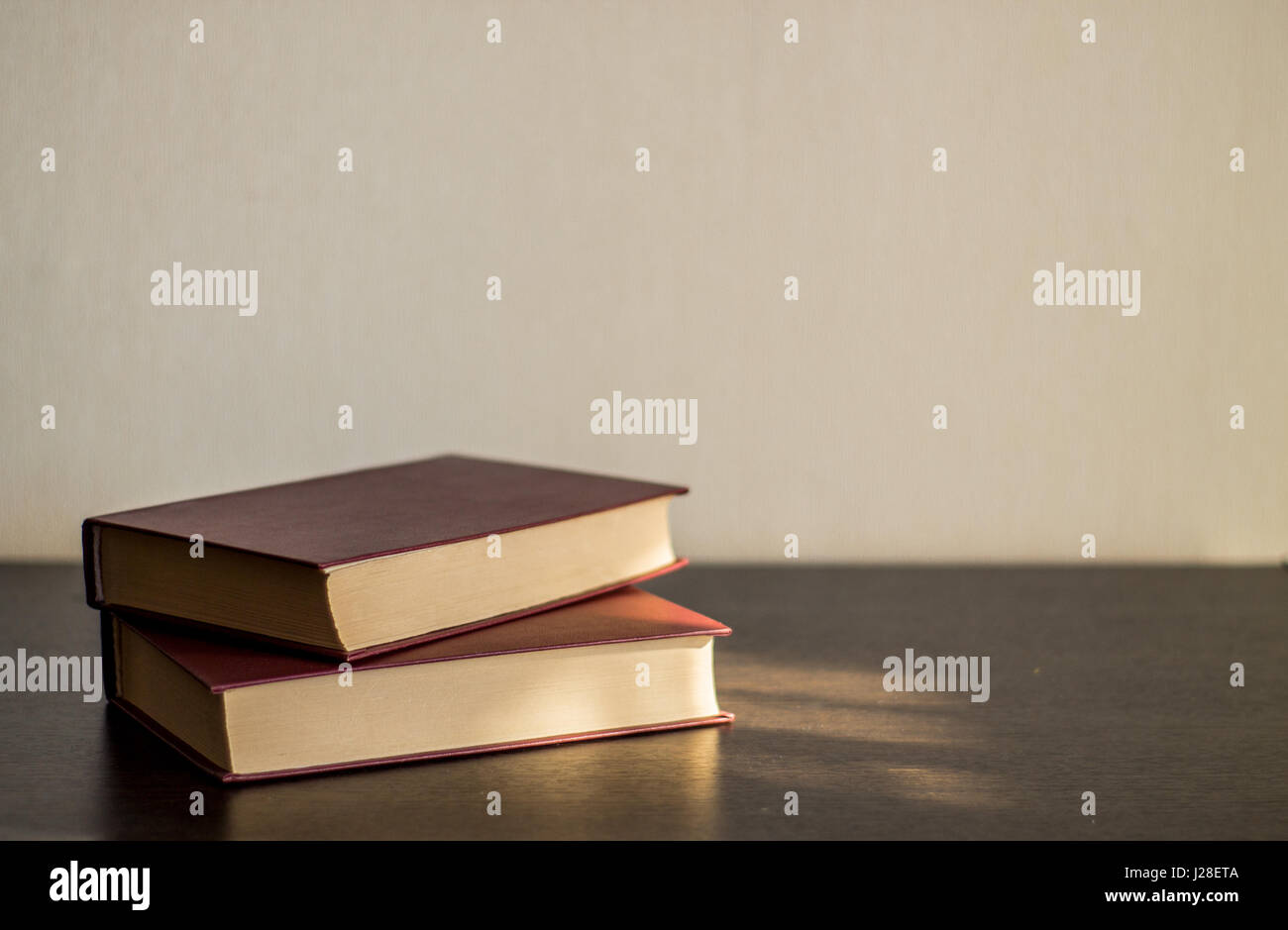 Two books on an empty wooden table. Behind it is a light background ...