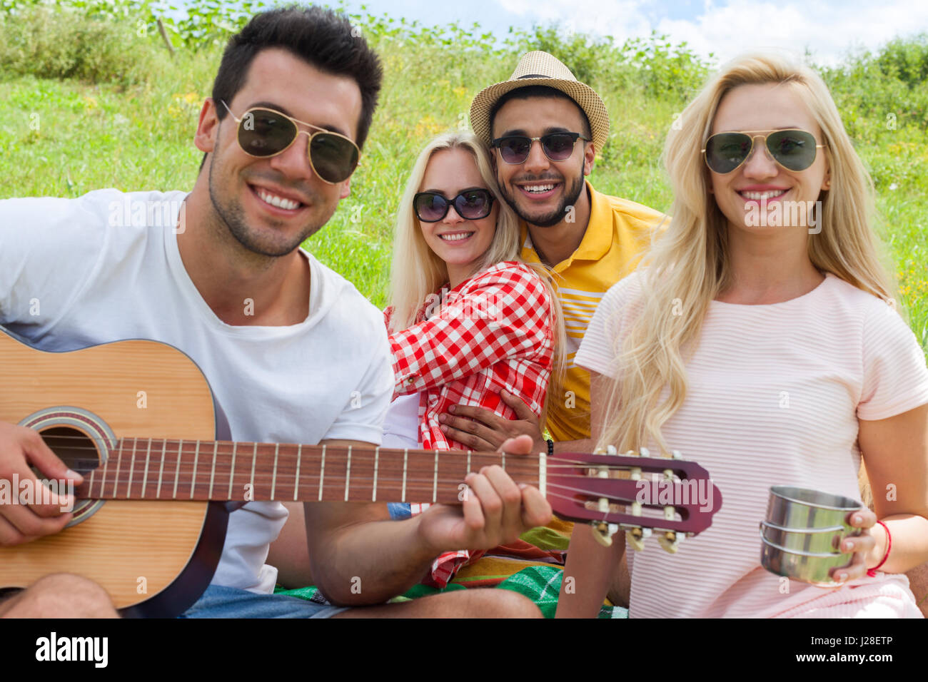 Young people listening guy playing guitar group friends summer day ...