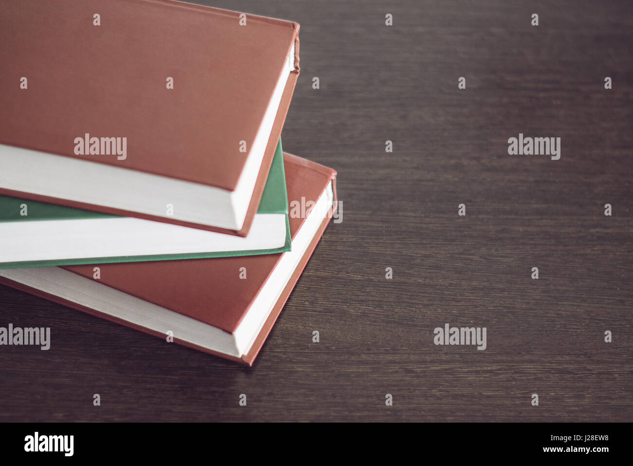 Three books on an empty wooden table Stock Photo - Alamy
