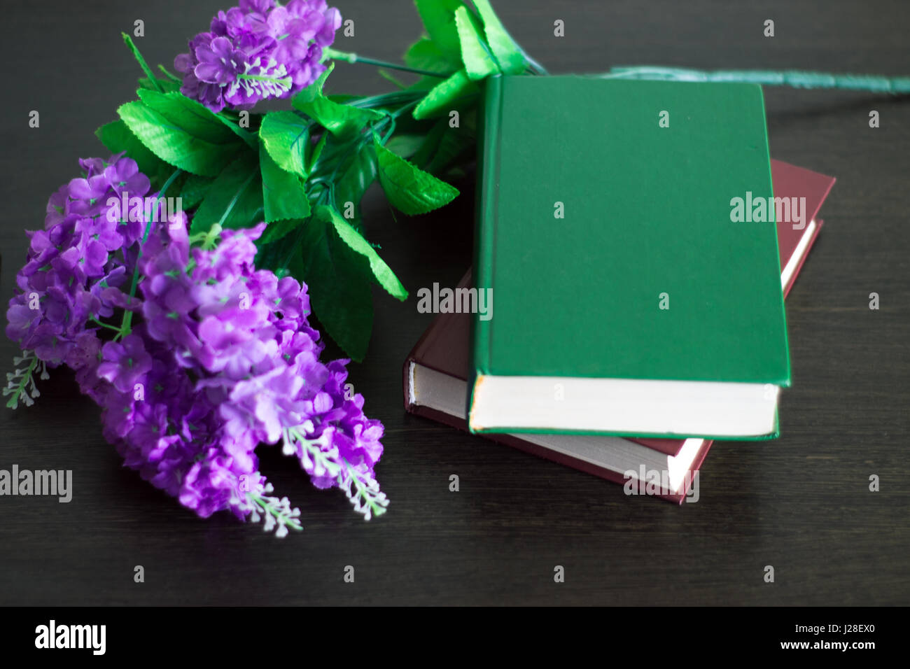 Books with purple flowers on a wood table Stock Photo - Alamy