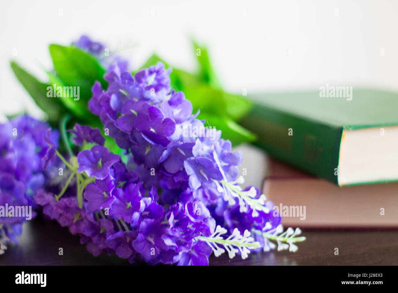 Books with purple flowers on a wood table Stock Photo - Alamy