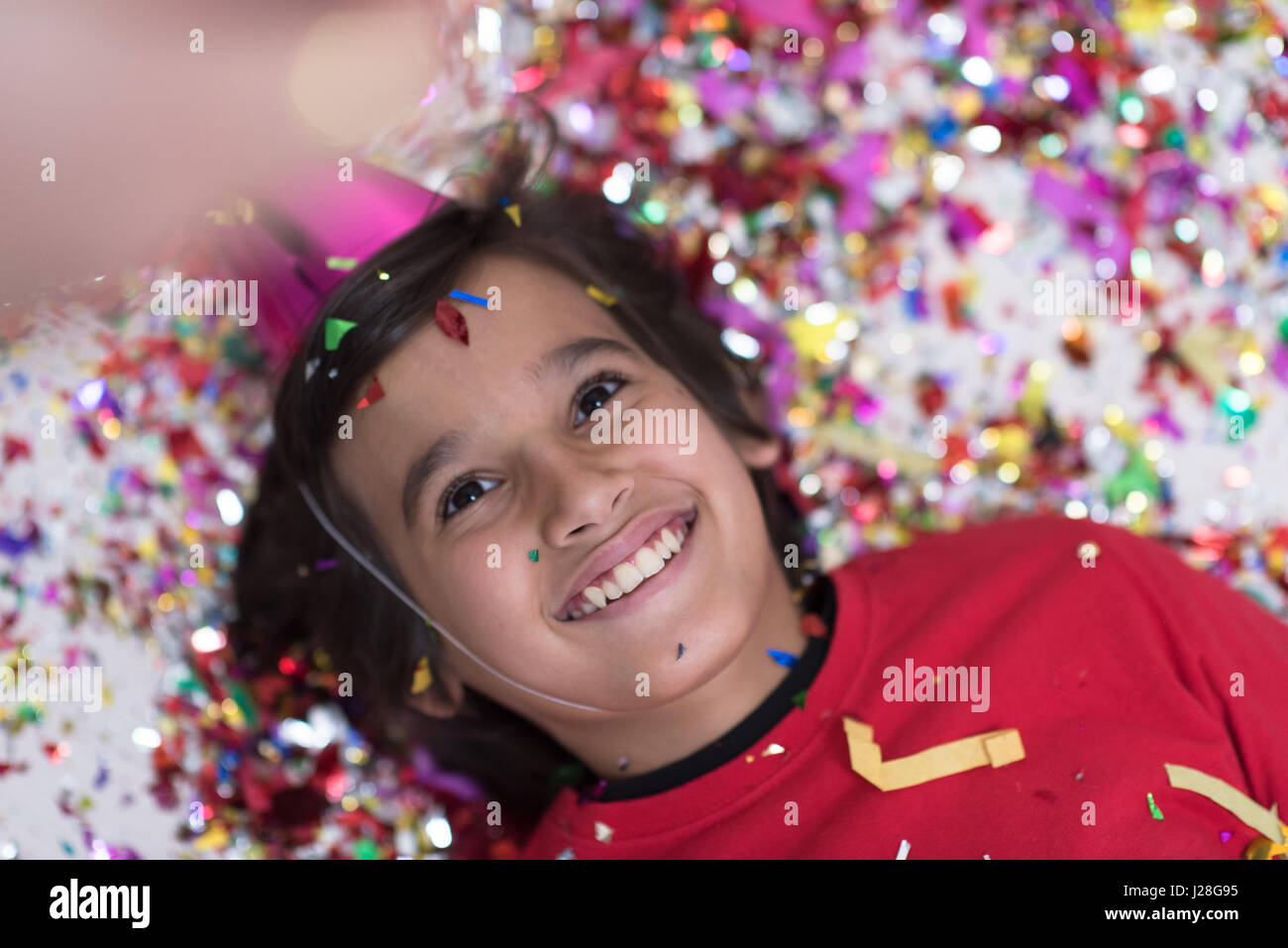 Happy kid celebrating party with blowing confetti while lying on the ...