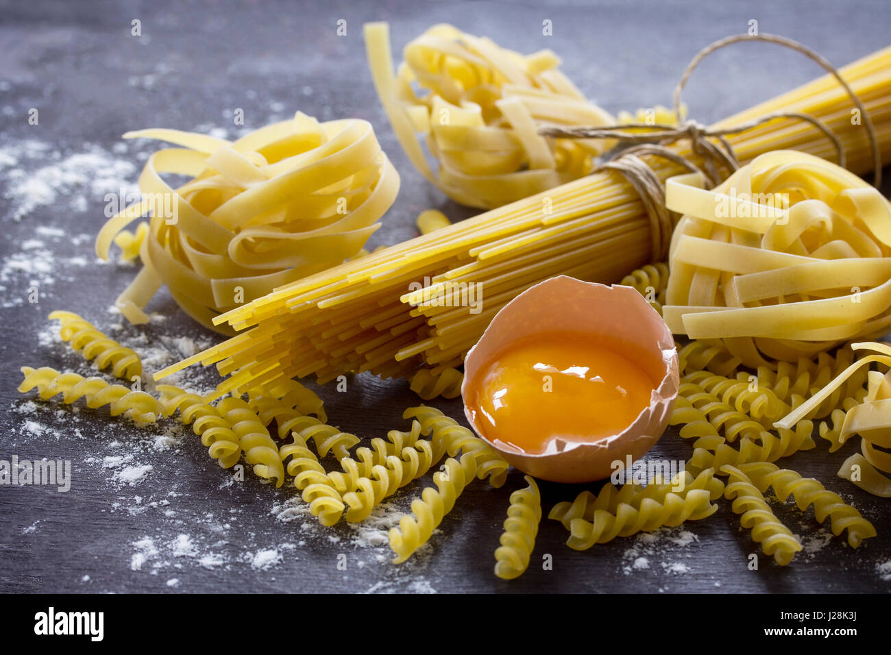 Different kinds of pasta spaghetti, fusilli, fettuccine and raw egg ...