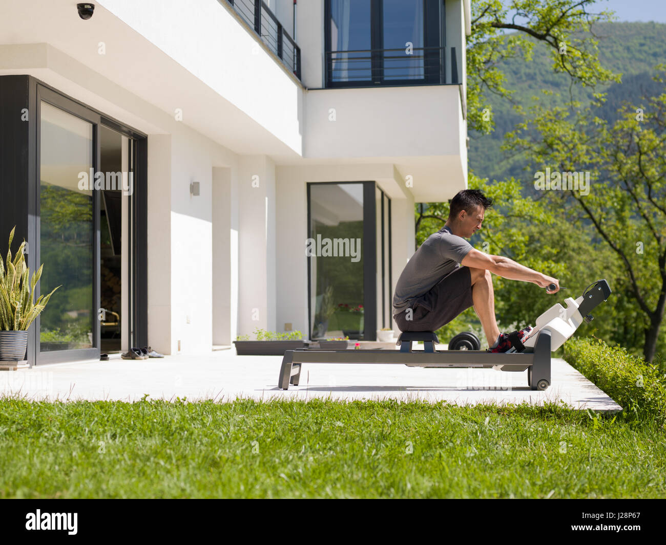 young handsome man doing morning exercises in front of his luxury home ...