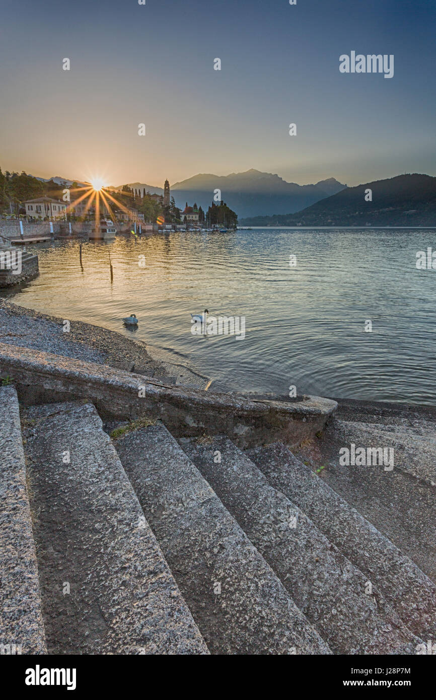 Steps leading to lake with swans at sunrise with the sun rising at dawn ...