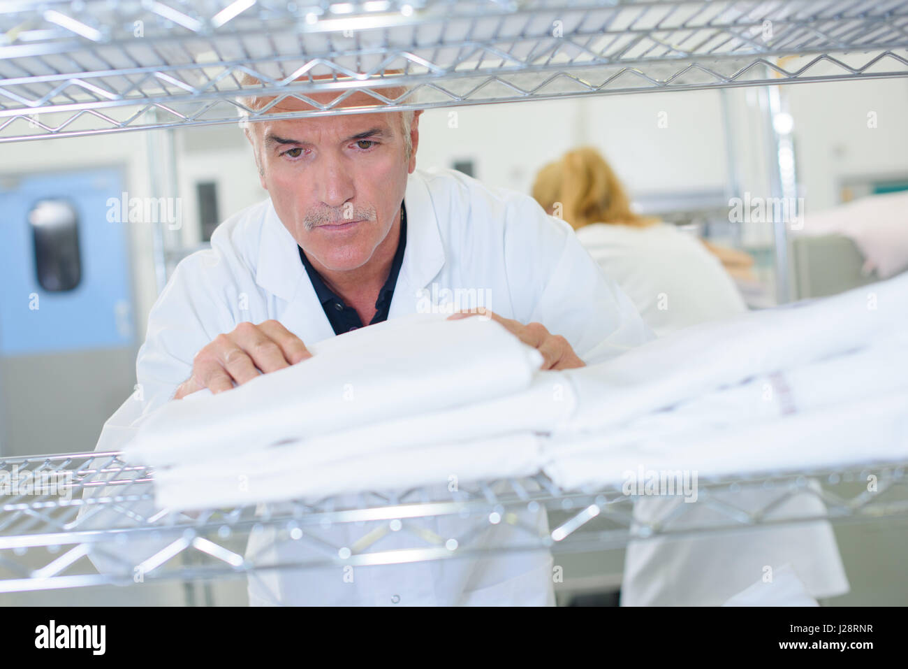 Man stacking towel on shelf Stock Photo - Alamy