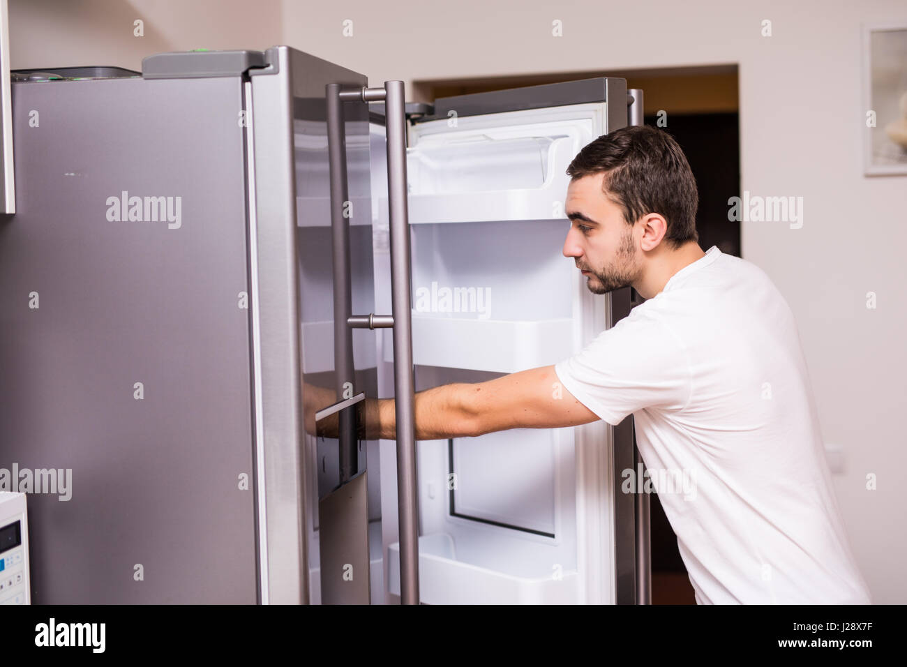 Man open refrigerator door in the kitchen Stock Photo - Alamy