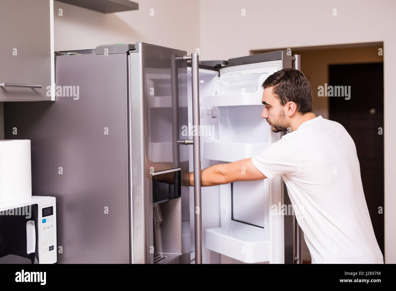 Man open refrigerator door in the kitchen Stock Photo - Alamy