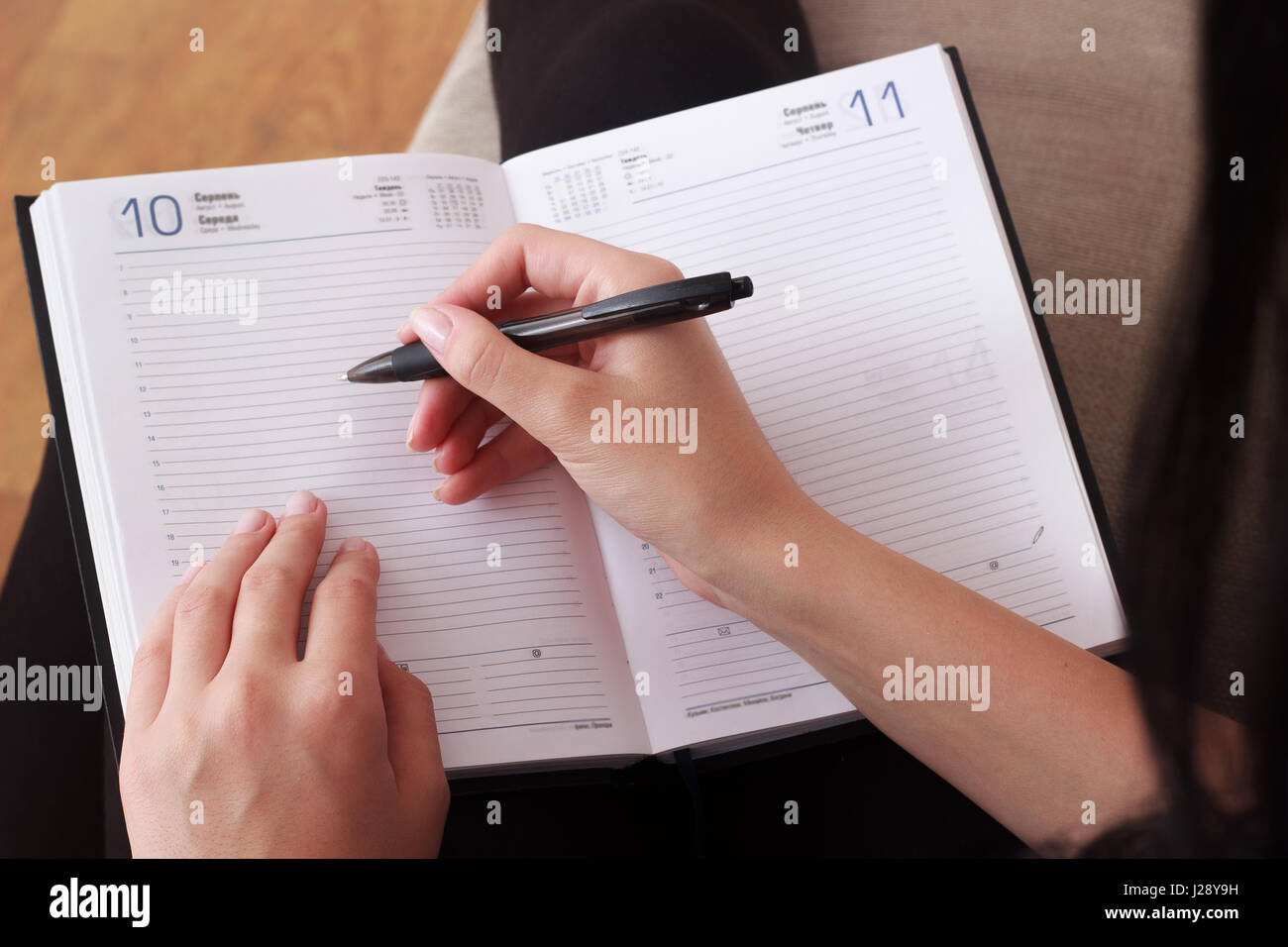 Hand is writing in a notepad on a wooden table Stock Photo - Alamy