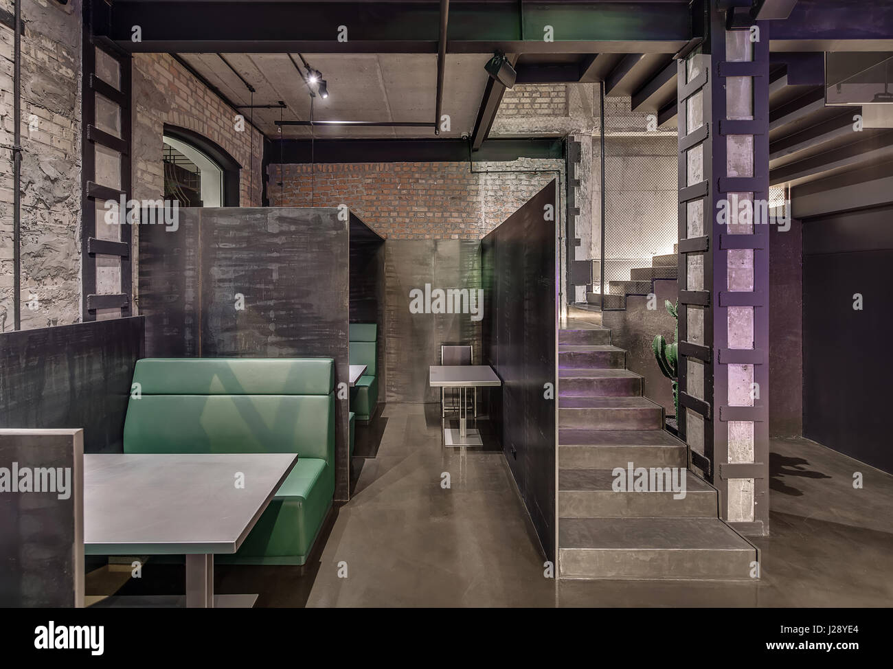 Loft style cafe with brick and concrete walls, column, stairway with ...