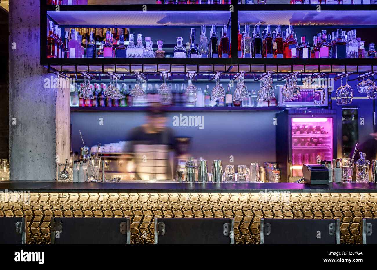 Luminous bar with a concrete column and a rack with the gold metal ...