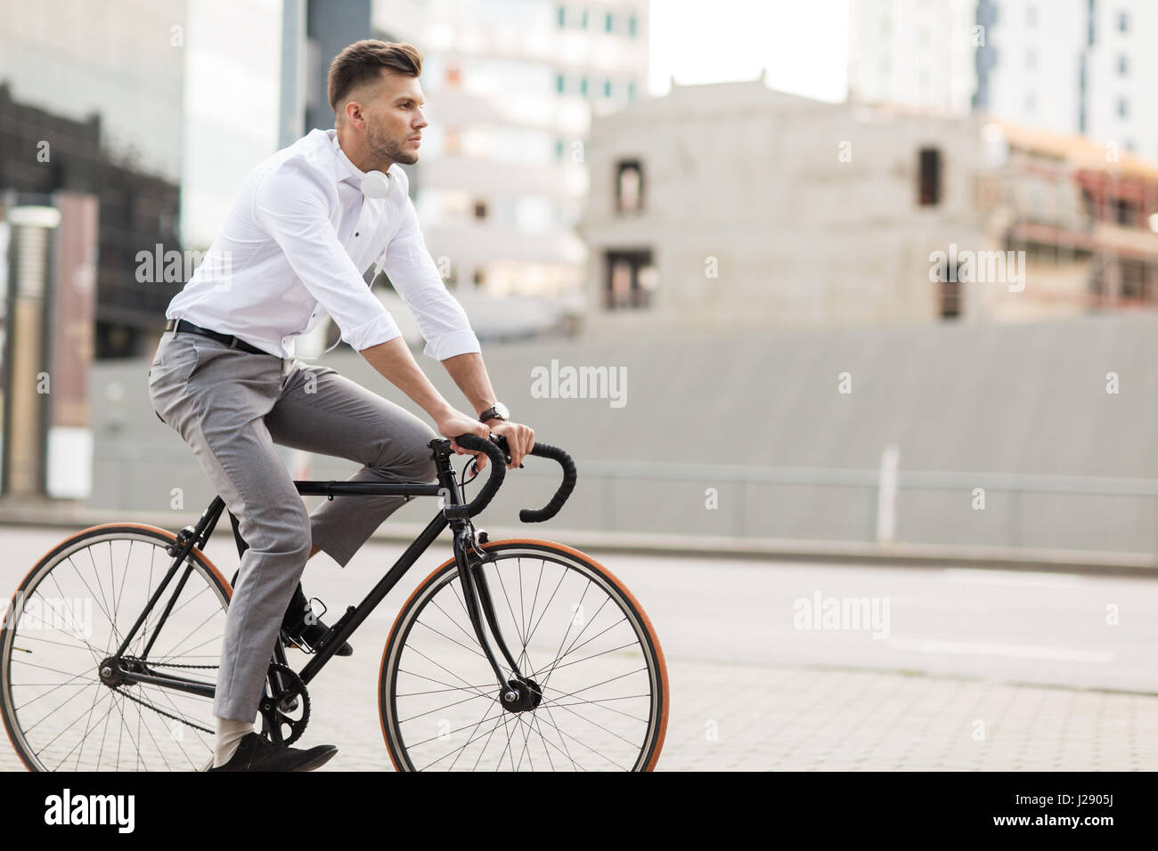 man with headphones riding bicycle on city street Stock Photo - Alamy