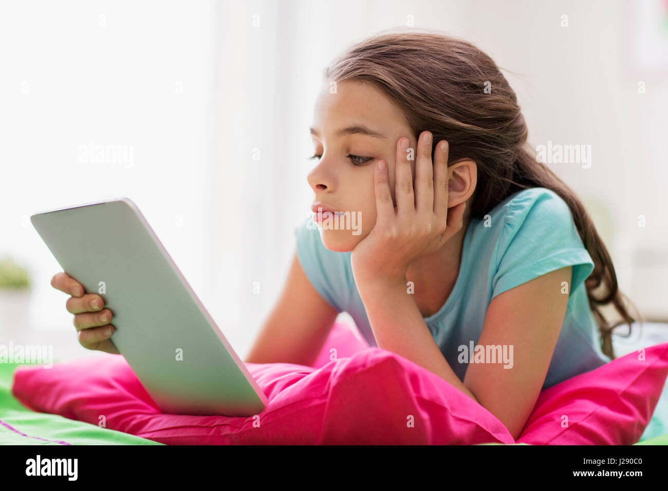 bored girl with tablet pc lying in bed at home Stock Photo - Alamy