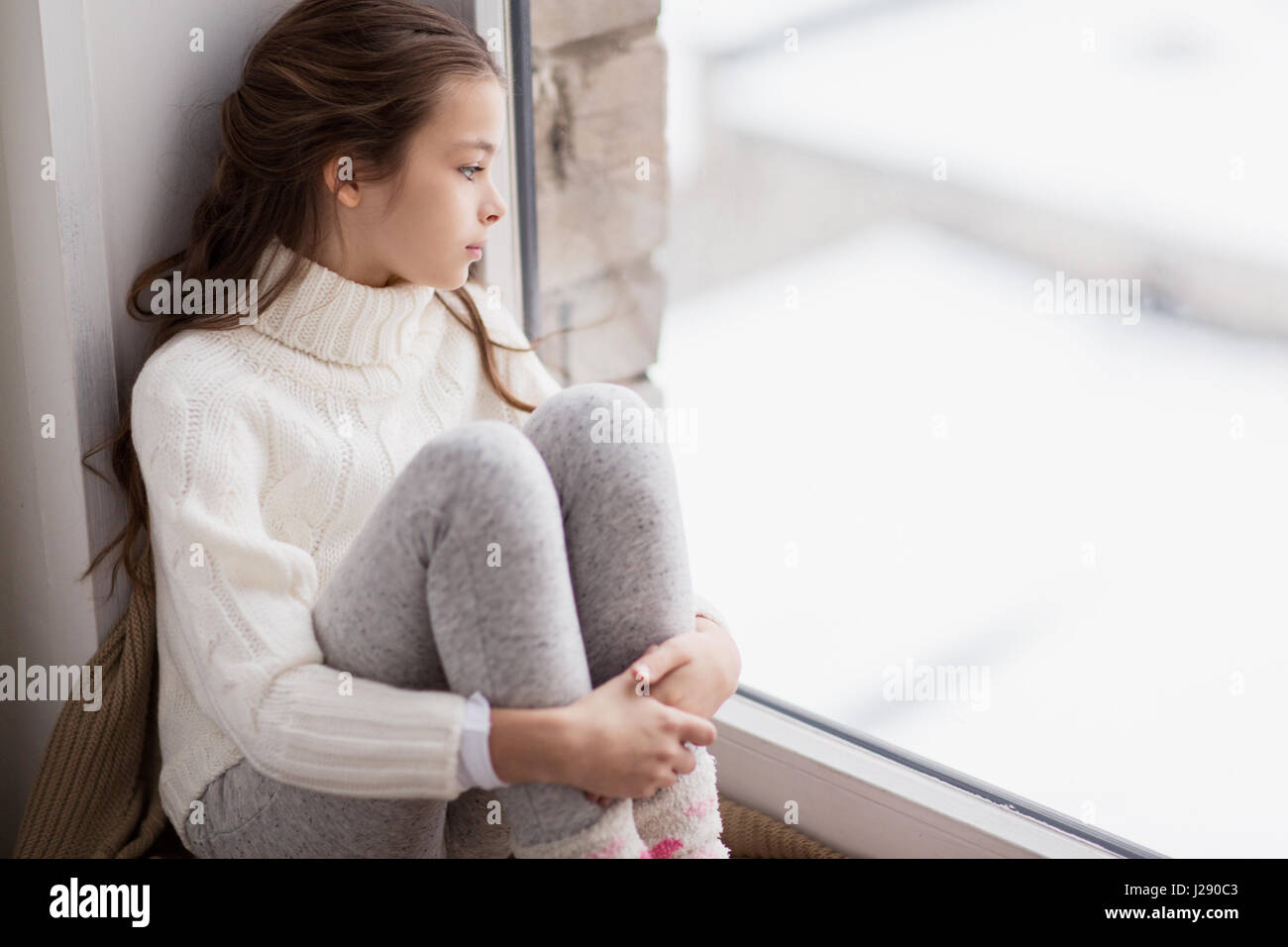 sad girl sitting on sill at home window in winter Stock Photo - Alamy