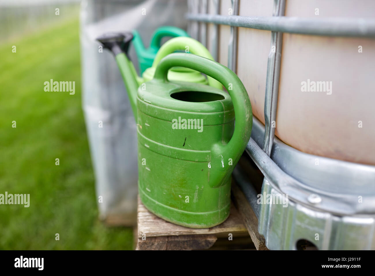 watering cans at farm water tank Stock Photo - Alamy