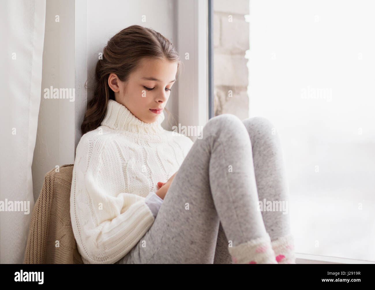 sad girl sitting on sill at home window in winter Stock Photo - Alamy