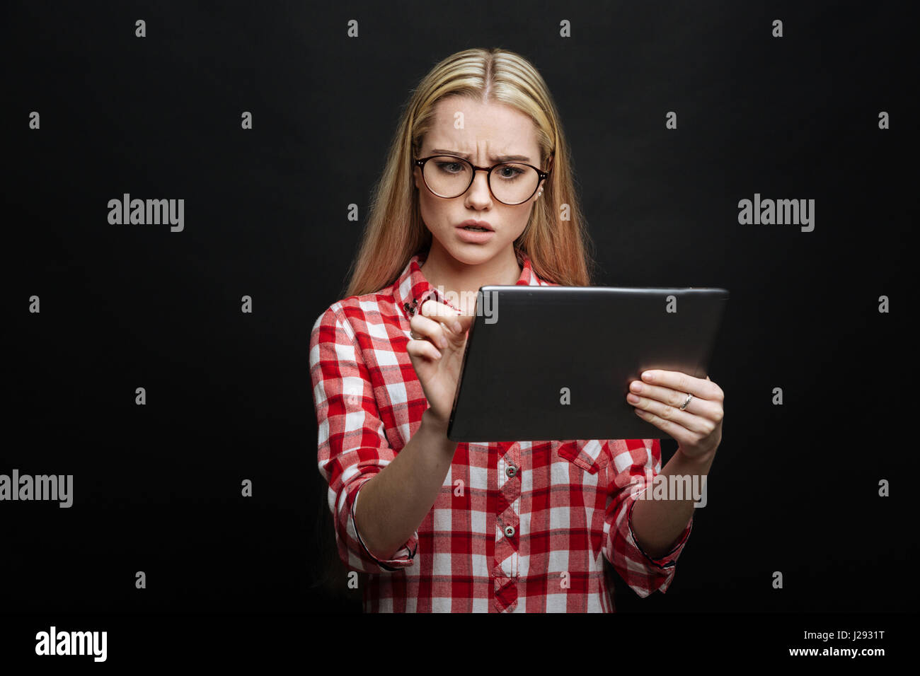 Puzzled young girl using electronic device in the studio Stock Photo ...