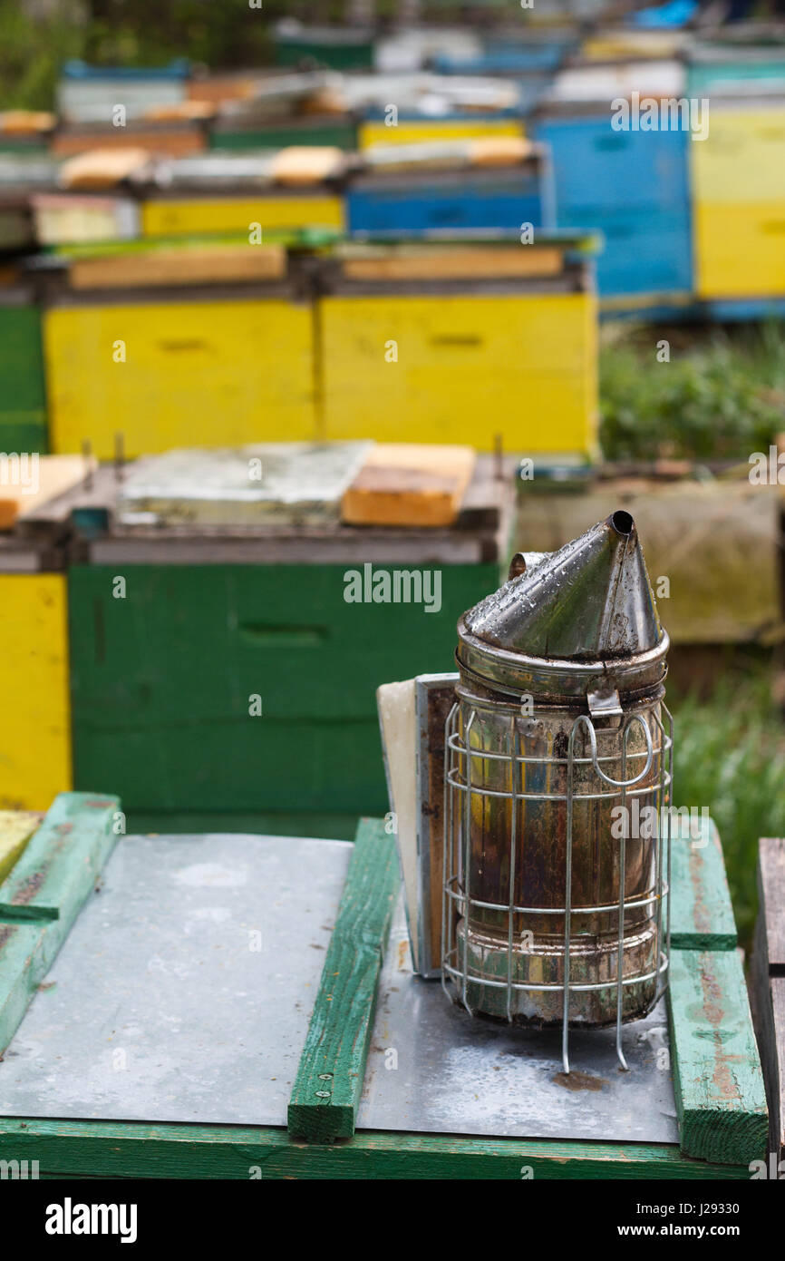 vertical view of metallic bee smoker equipment on top of beehives boxes ...