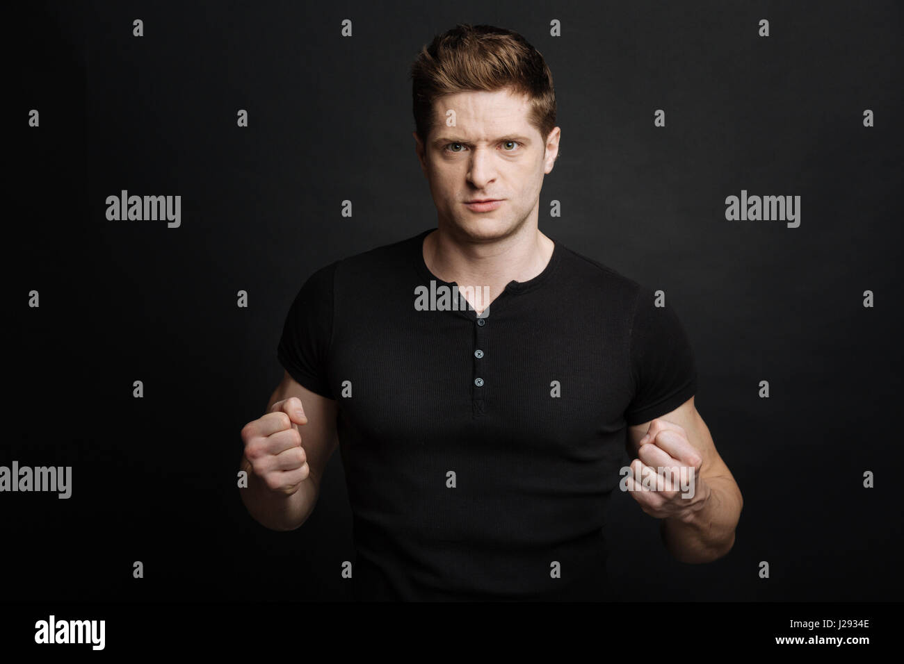 Angry young man expressing aggression against black background Stock ...