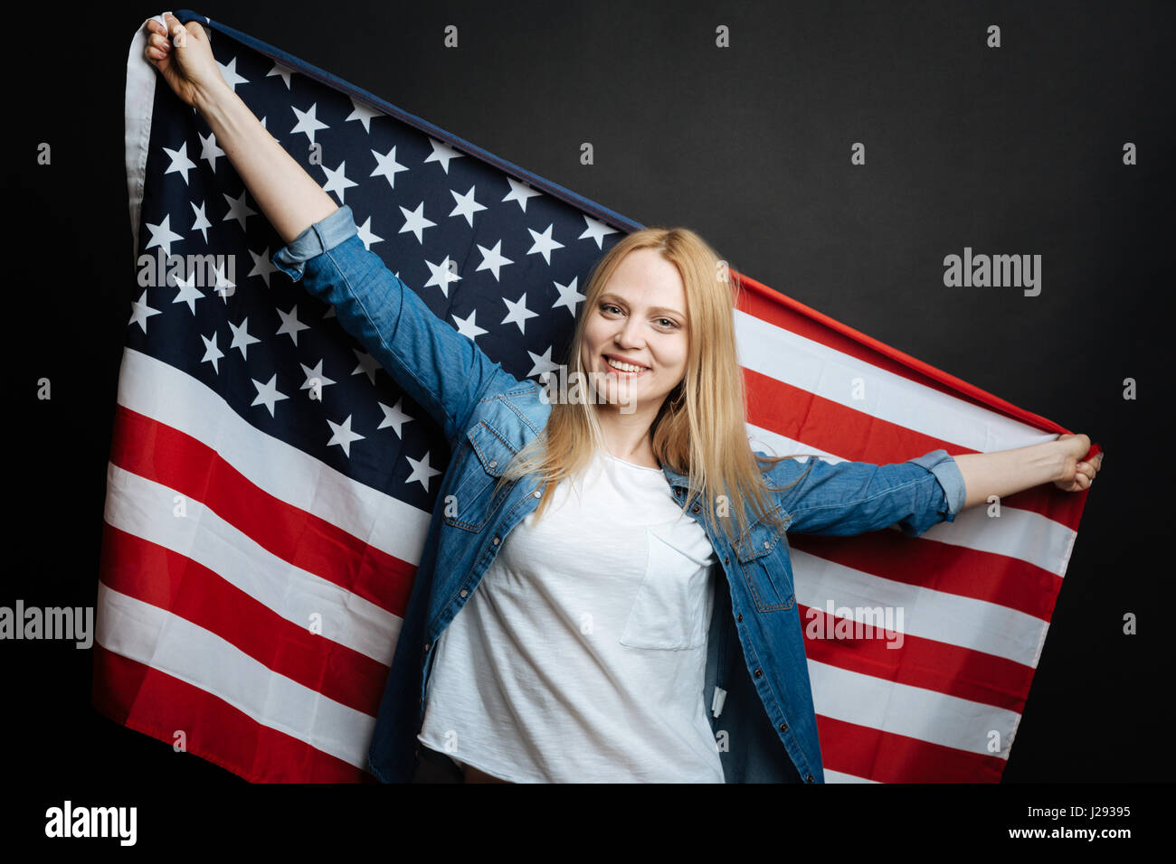 Joyful adult holding American flag in the studio Stock Photo - Alamy