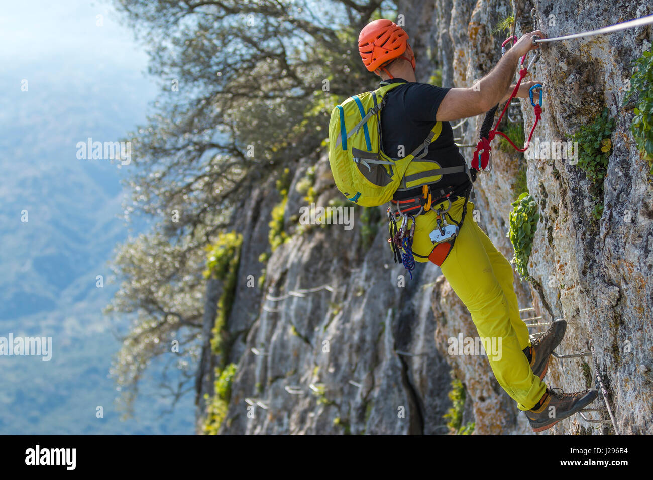 Male climber in special outfit climbing cliff with mountaineering ...