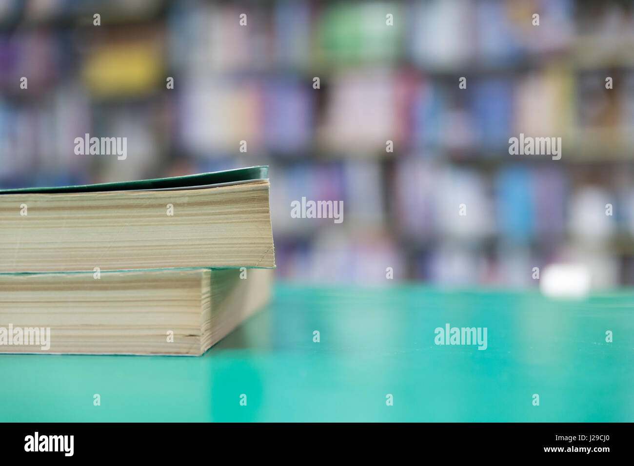 A stack of old books on table with blur book shelf in library room ...