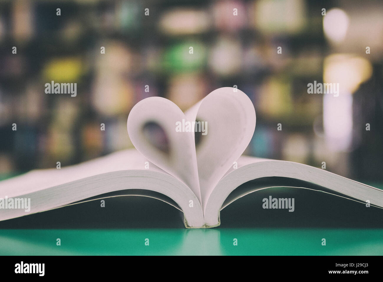 open book page in heart shape with library background, love in ...