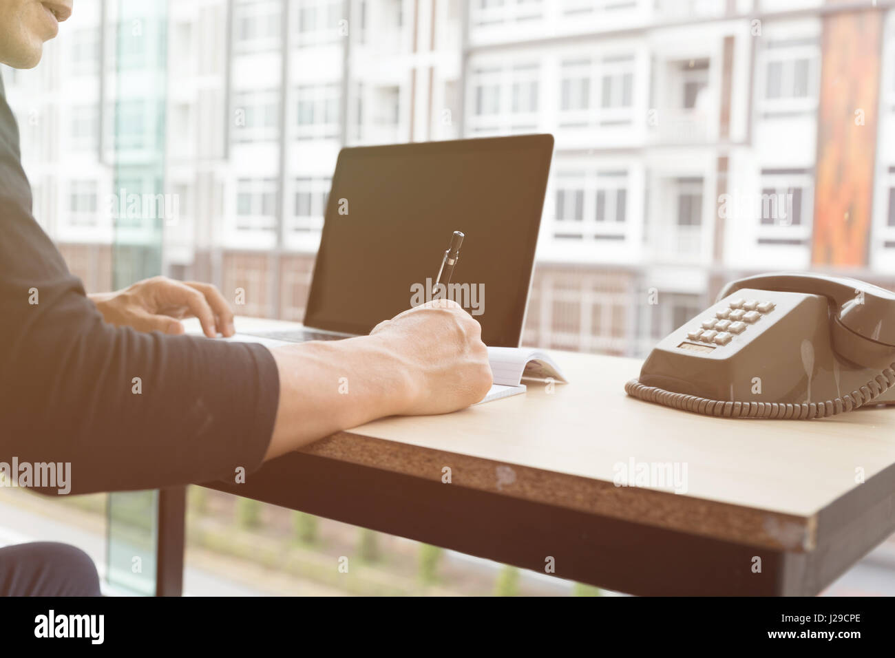 startup young man working on laptop computer, writing note while ...