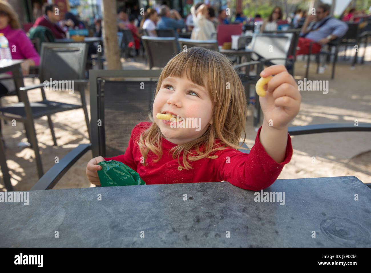 portrait of blonde three years old child, with red shirt, eating cheese ...