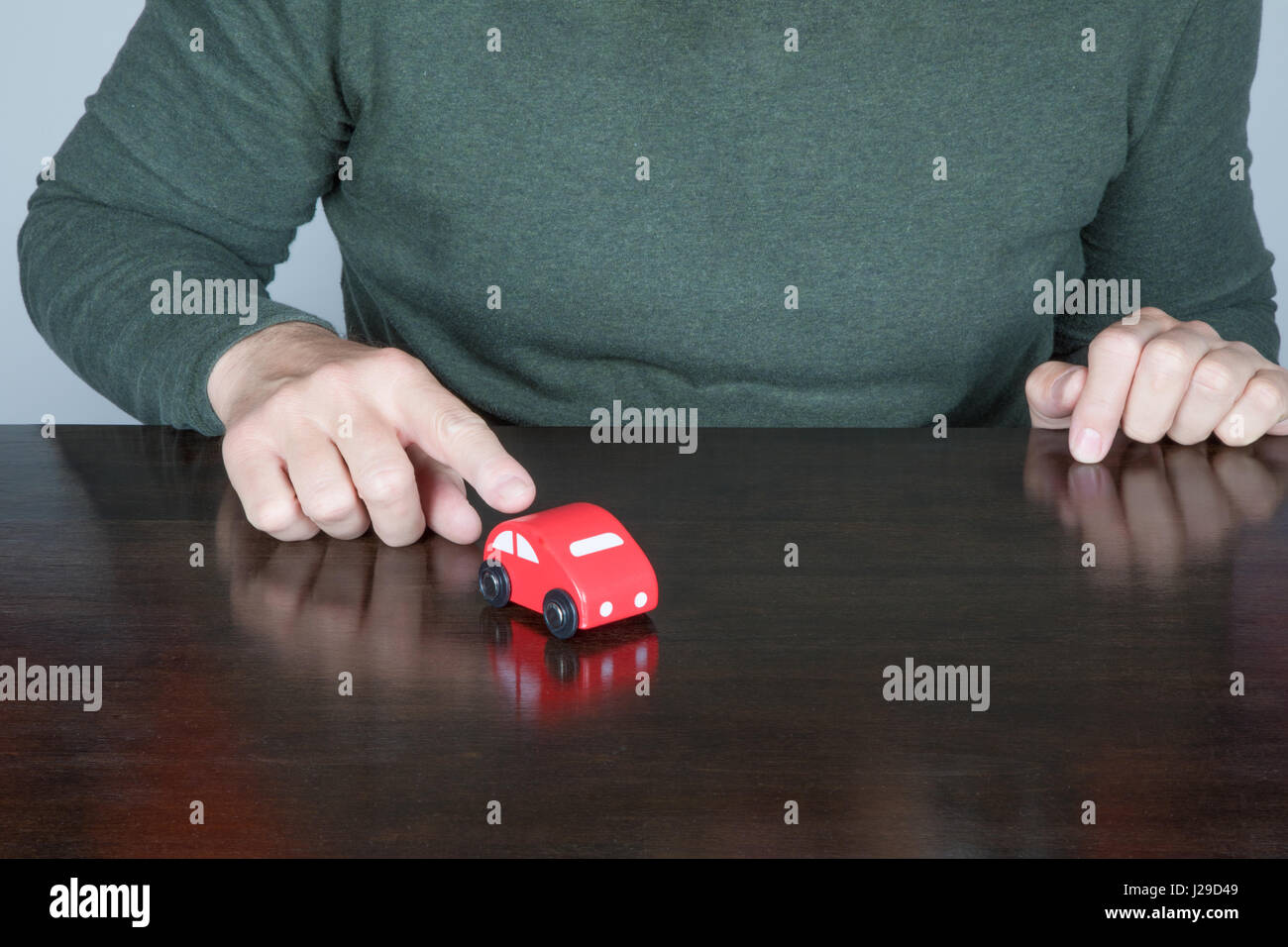 index finger of man with green shirt showing or pointing a red toy car ...