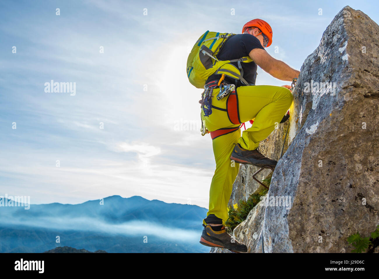 Male alpinist in special outfit climbing rock on background of summit ...