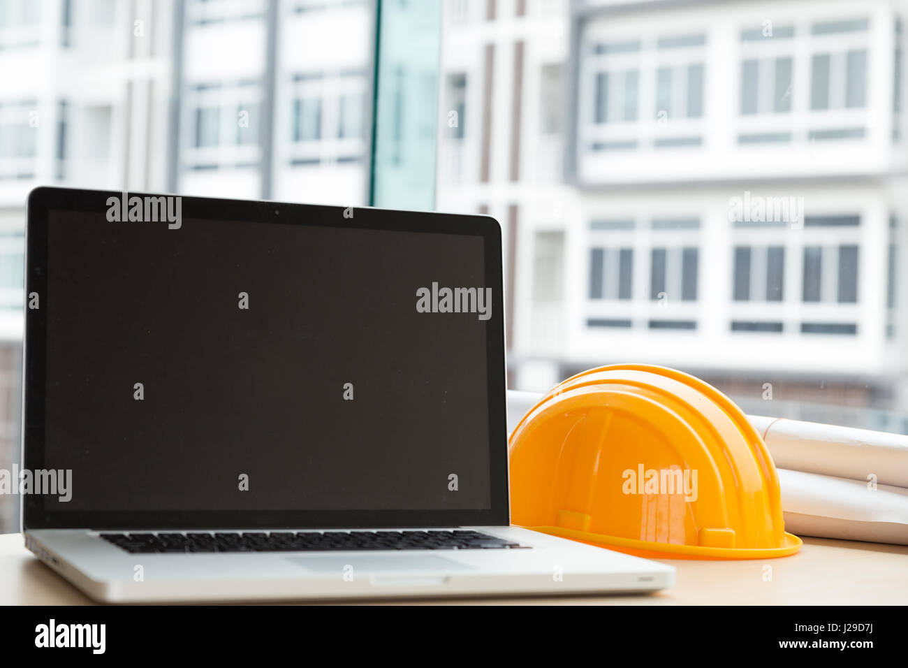 engineer desk with laptop computer, orange helmet, blueprint roll with ...