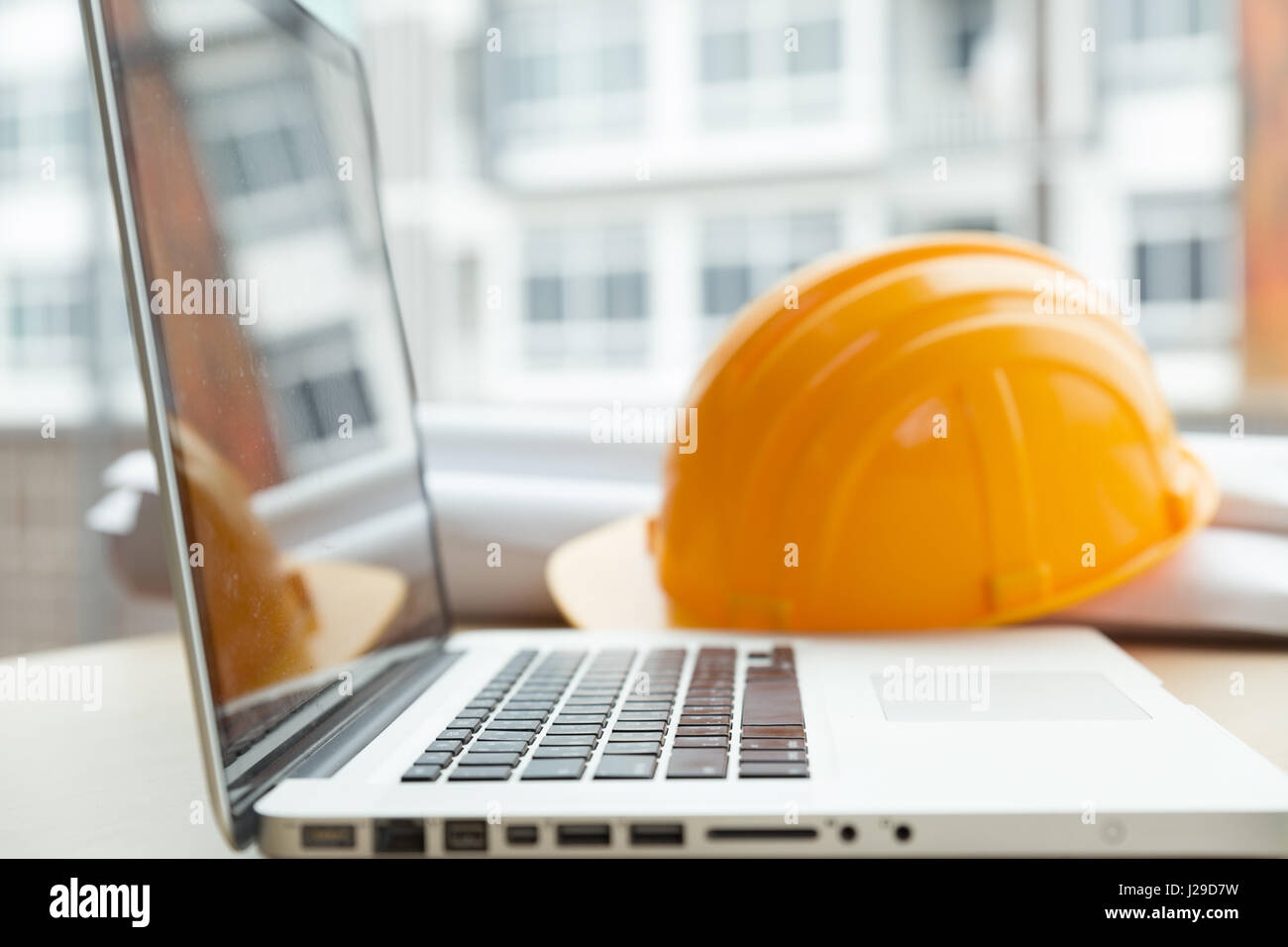 engineer desk with laptop computer, orange helmet, blueprint roll with ...